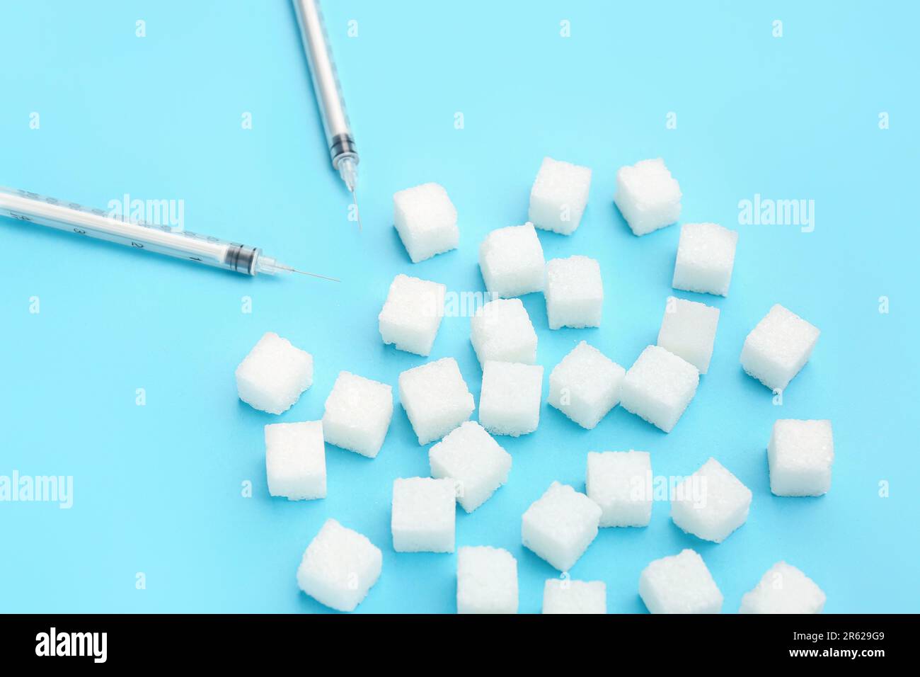 Sugar cubes with syringes for insulin injection on blue background ...