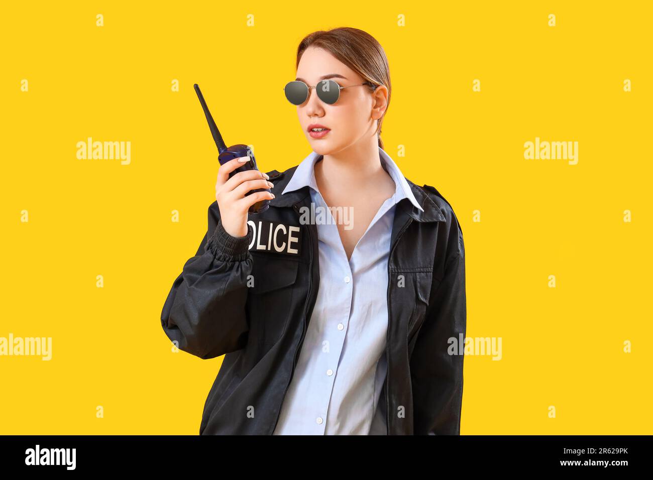 Female police officer with radio transmitter on yellow background Stock ...