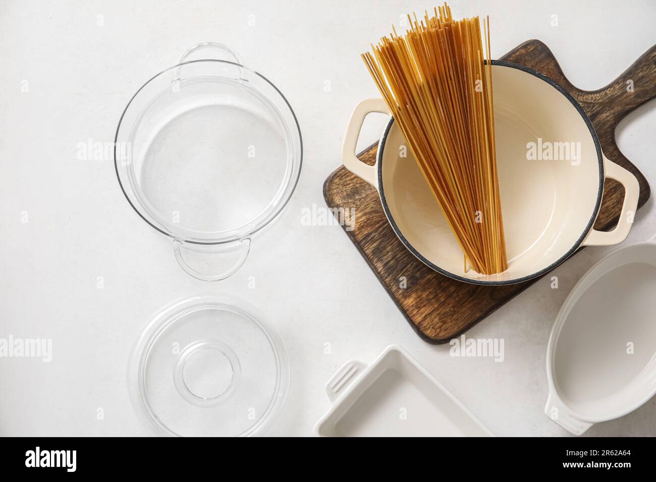 Set of kitchen utensils and pot with raw pasta on white background ...