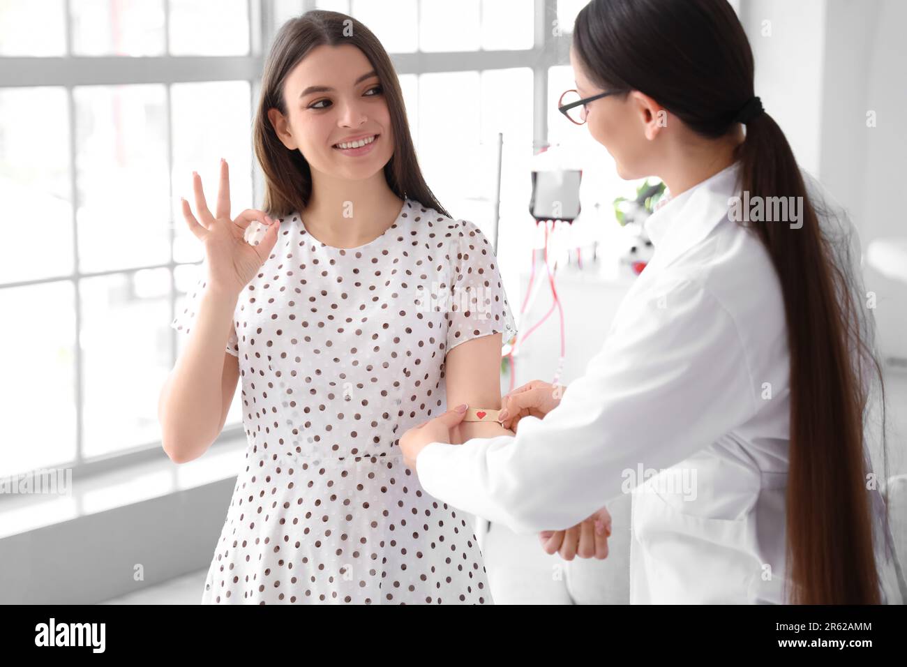 Female doctor applying medical patch on young donor's arm in clinic ...