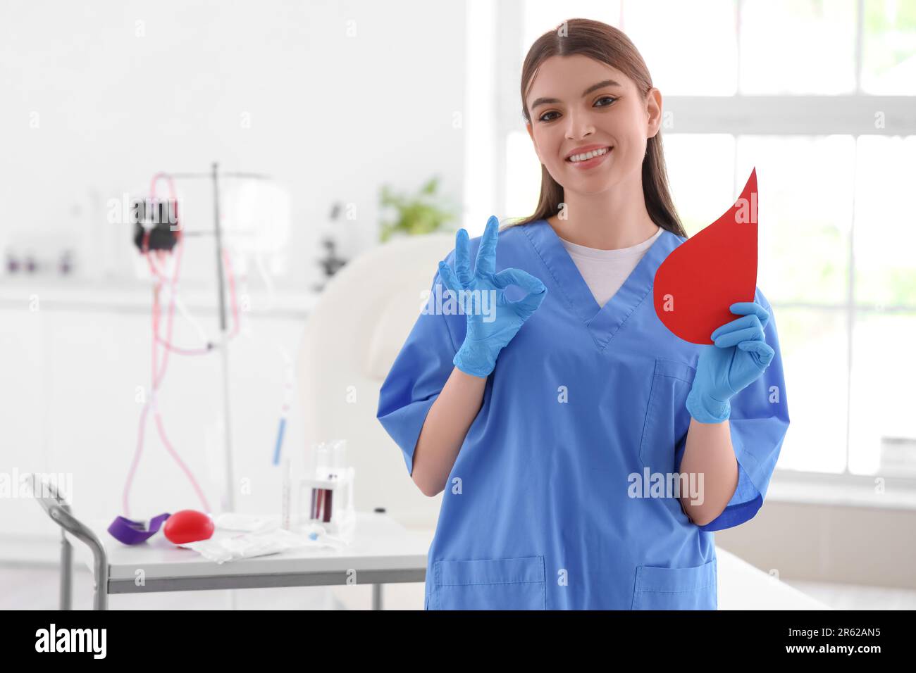 Female nurse with paper blood drop showing OK in clinic Stock Photo - Alamy