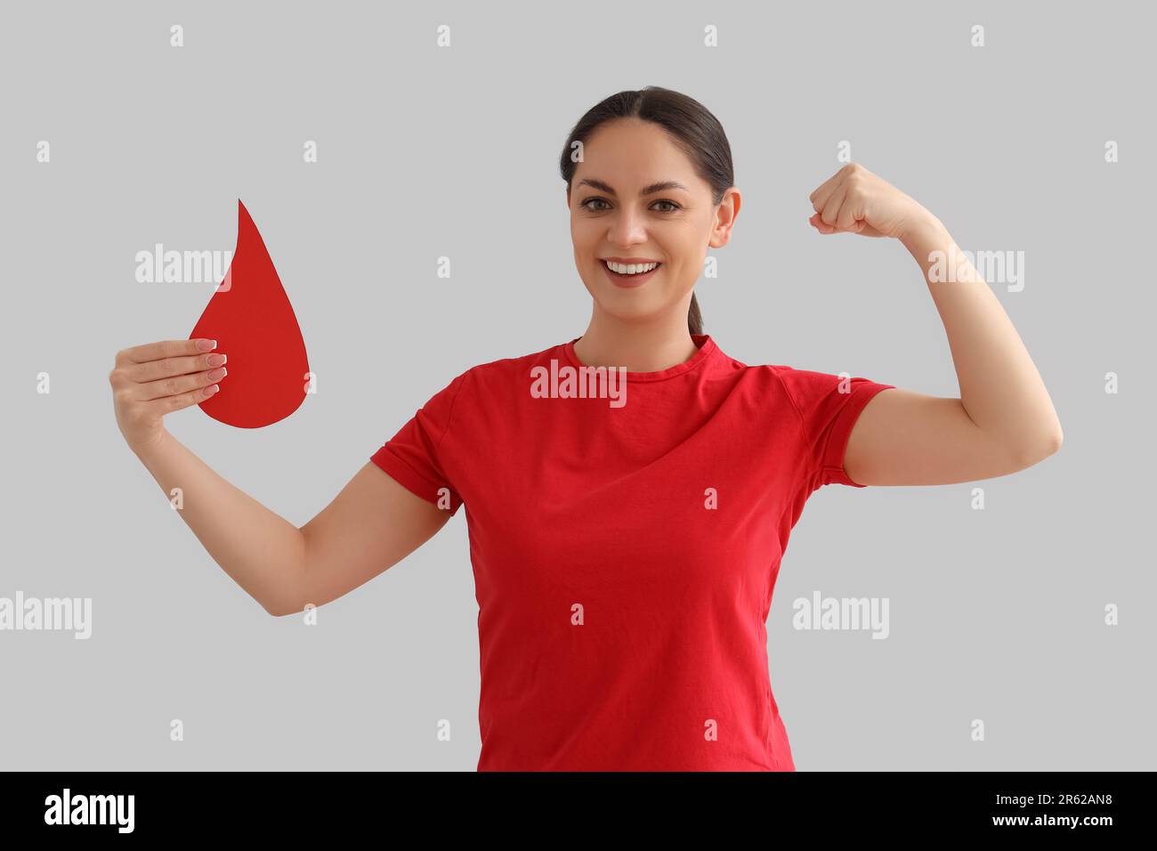 Female donor with paper blood drop showing muscles on light background ...