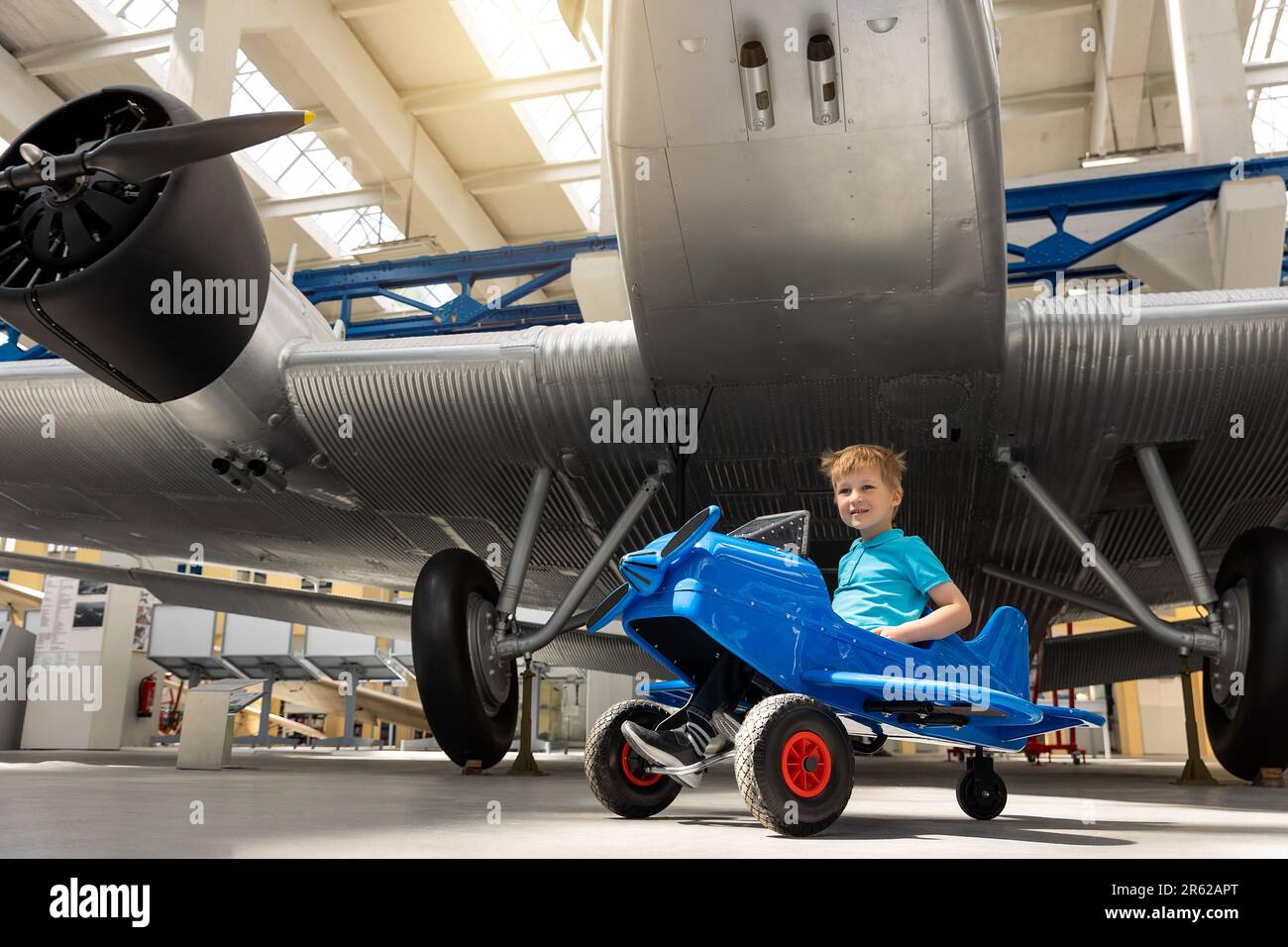 Portrait of cute little blond happy kid boy enjoy have fun play riding ...
