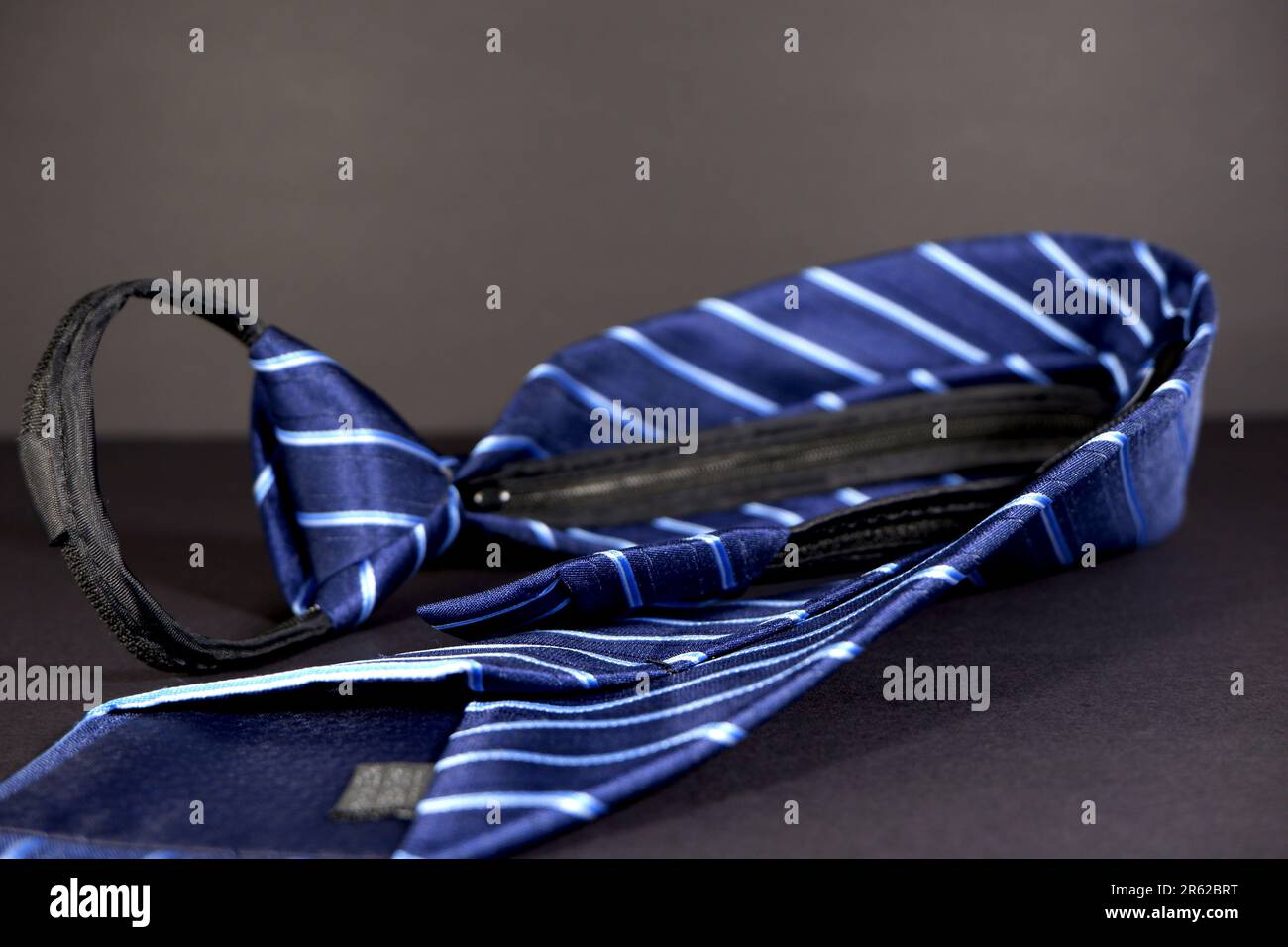 An open blue and white striped necktie lays flat on a table, creating a ...