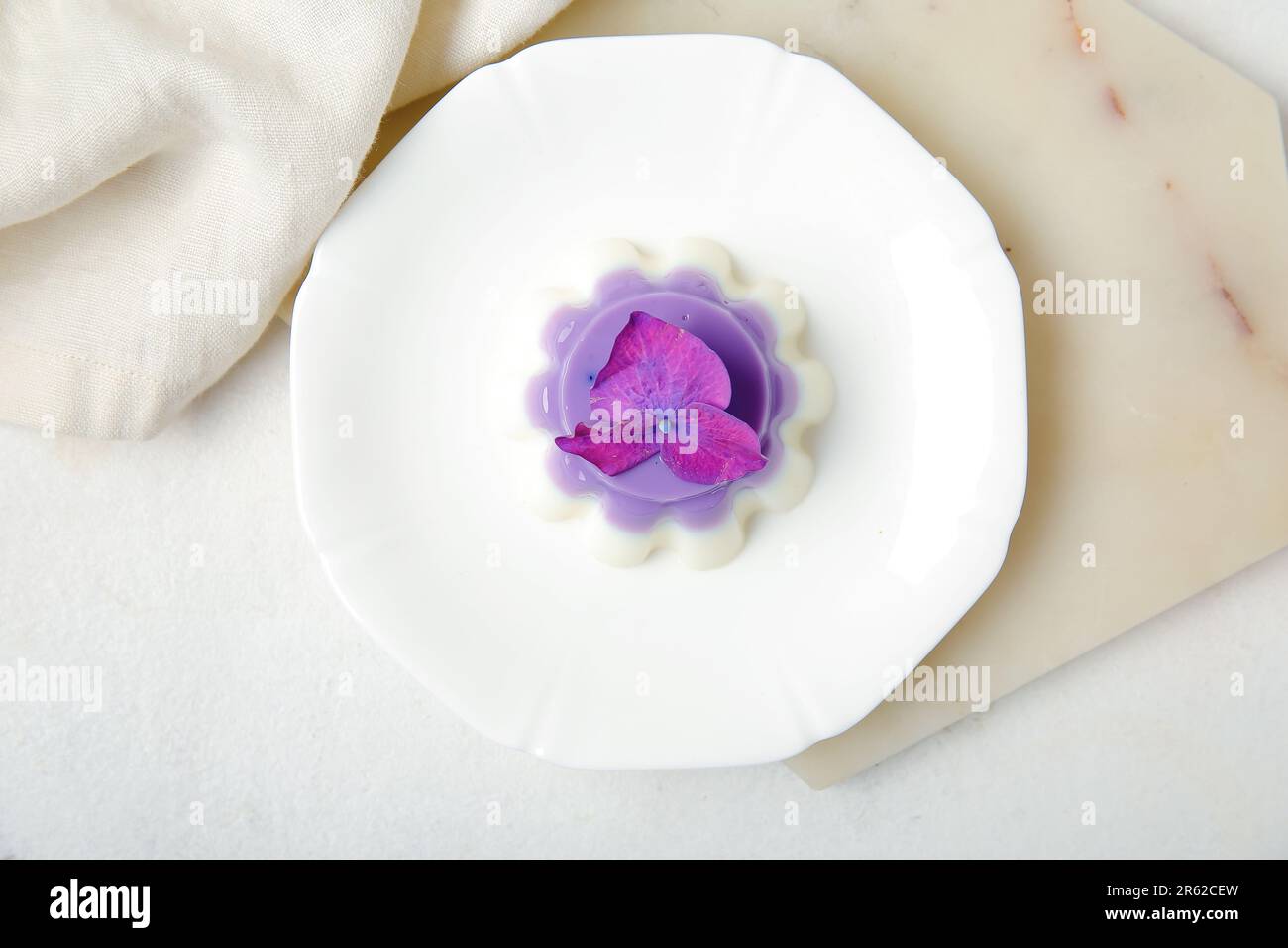 Plate of panna cotta with beautiful hydrangea flower on white table ...
