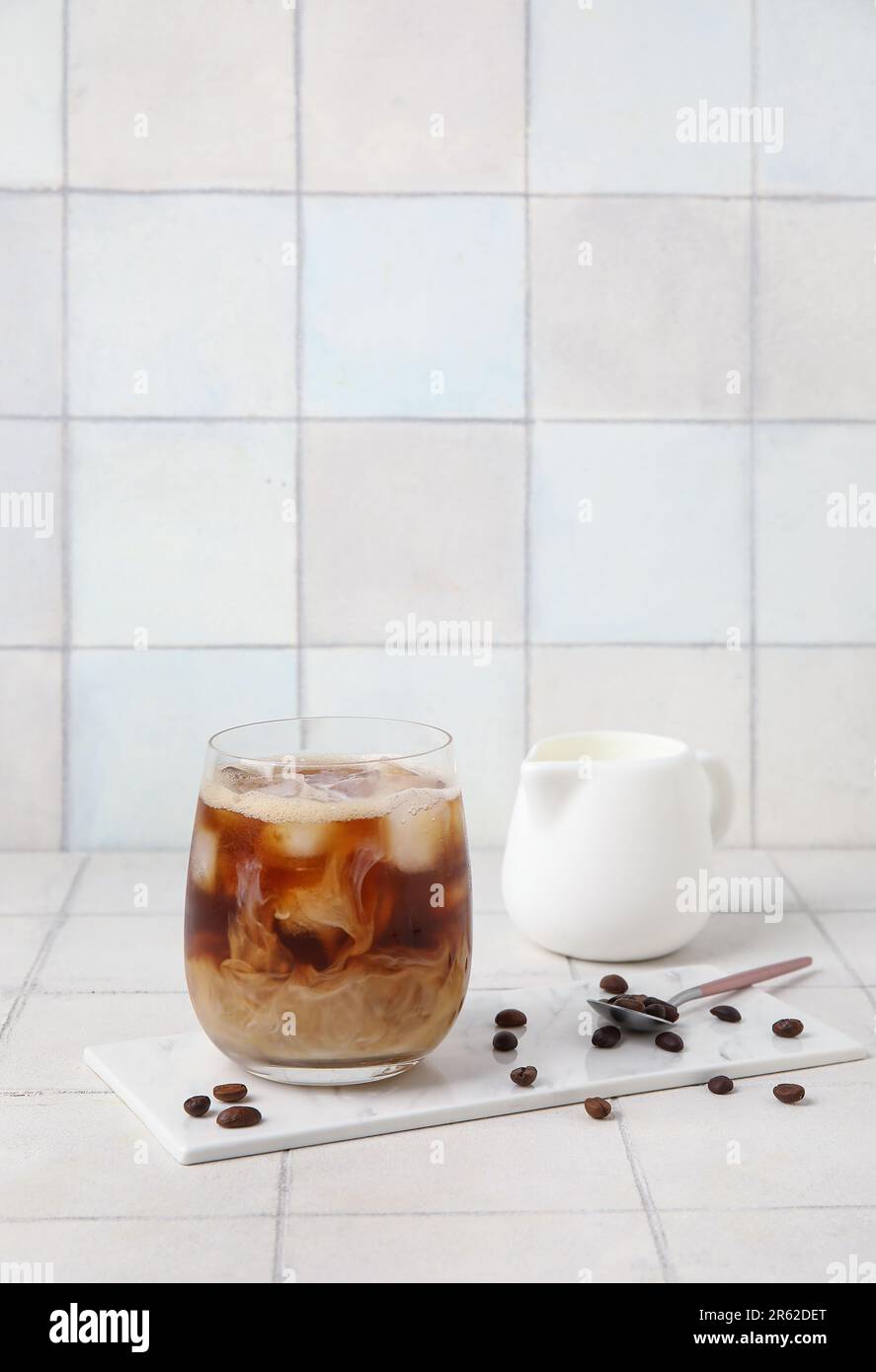 Glass of tasty ice coffee with milk on white tile background Stock ...