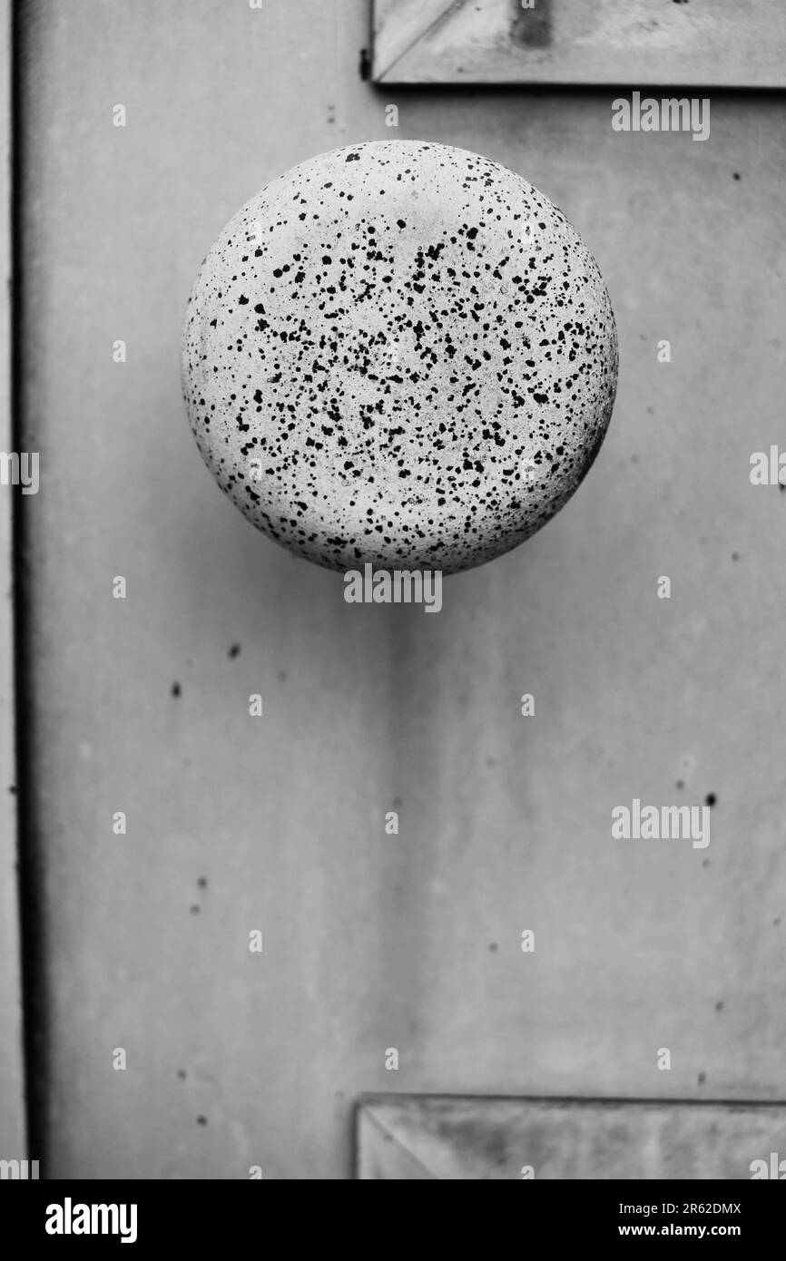 A round door handle cast in a copper metal door in a black and white ...