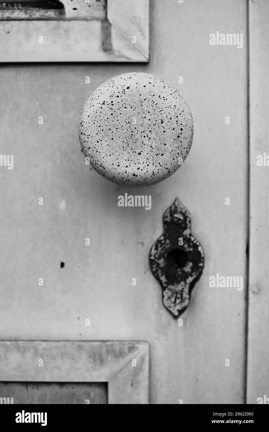 A round door handle cast in a copper metal door in a black and white ...