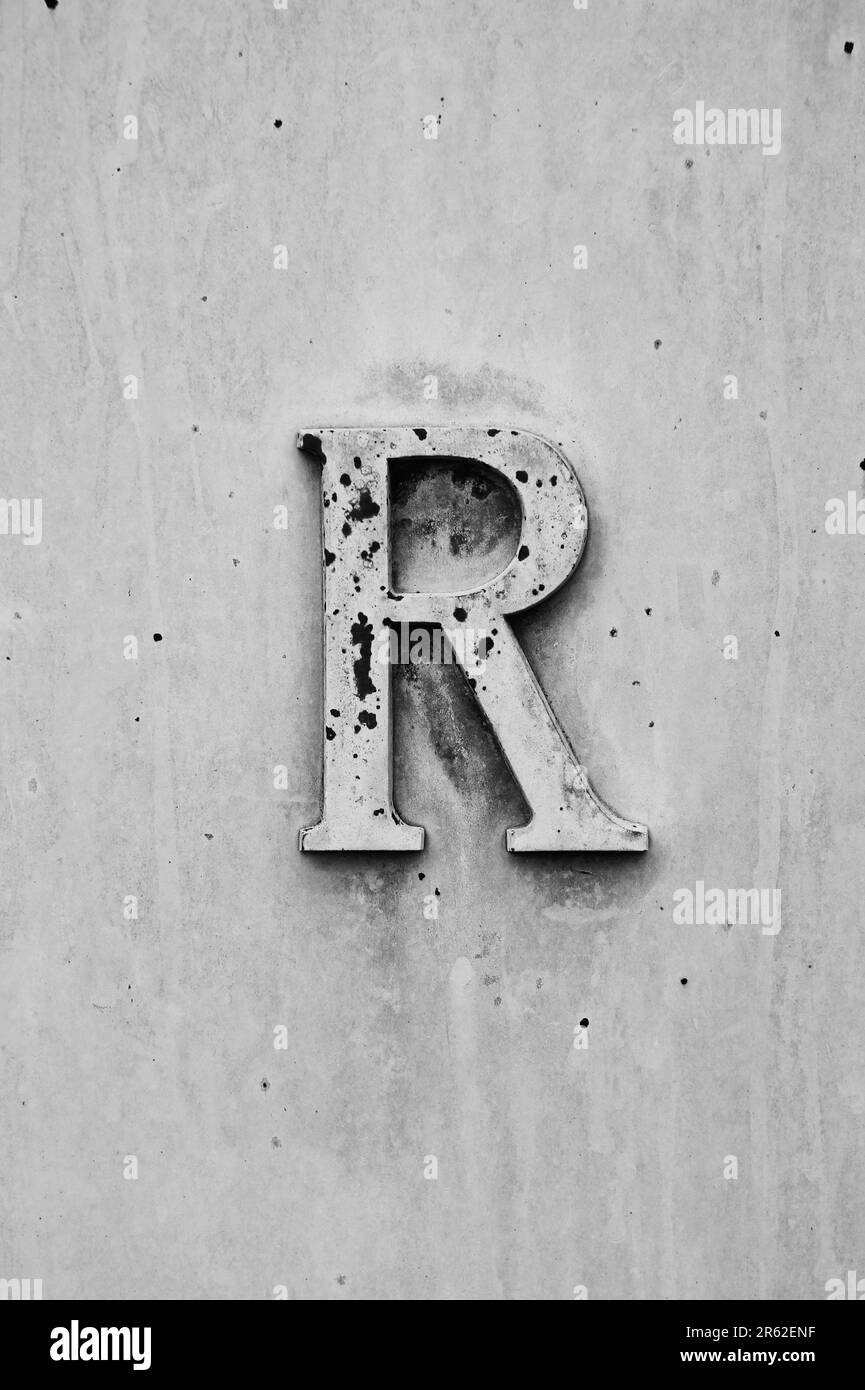 The capital letter R carved into a copper metal wall in a black and ...