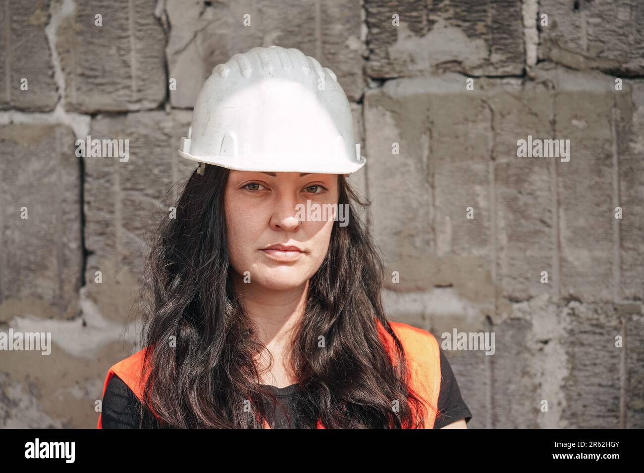 Young woman in white hard hat and orange high visibility vest, long ...