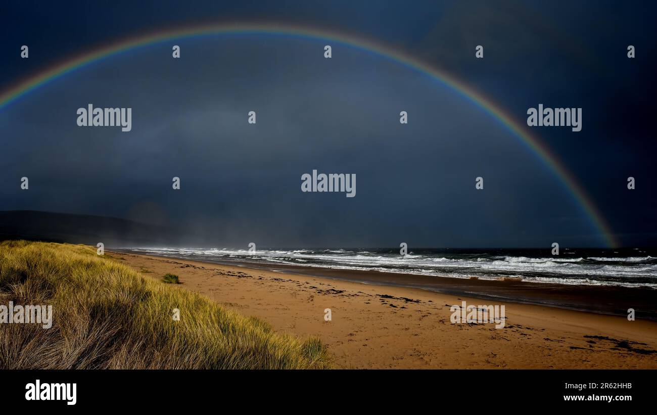 Heavy rain sweeping across a stormy sea with full rainbow over Brora ...