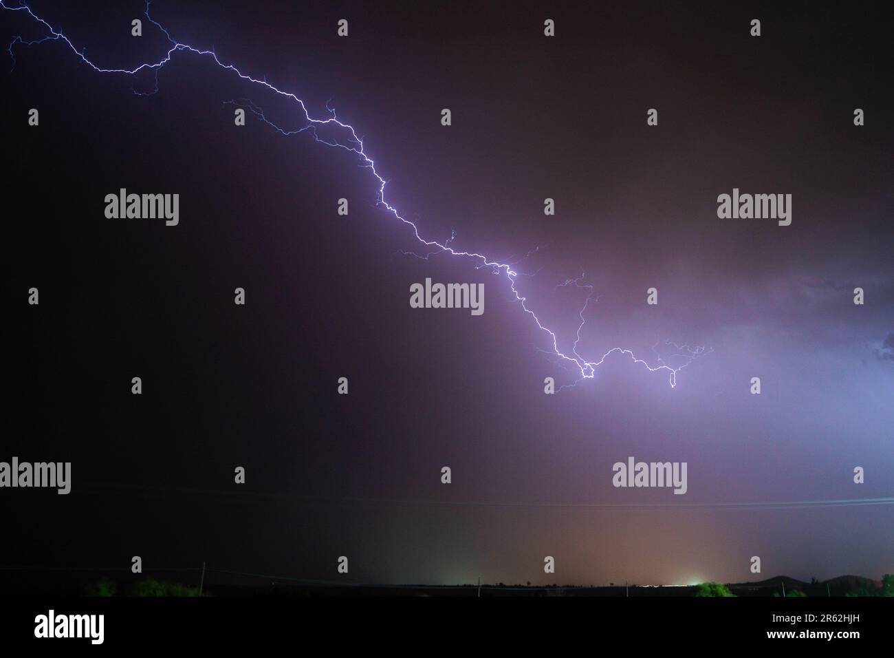 A dramatic image of a stormy night sky, with two lightning strikes ...