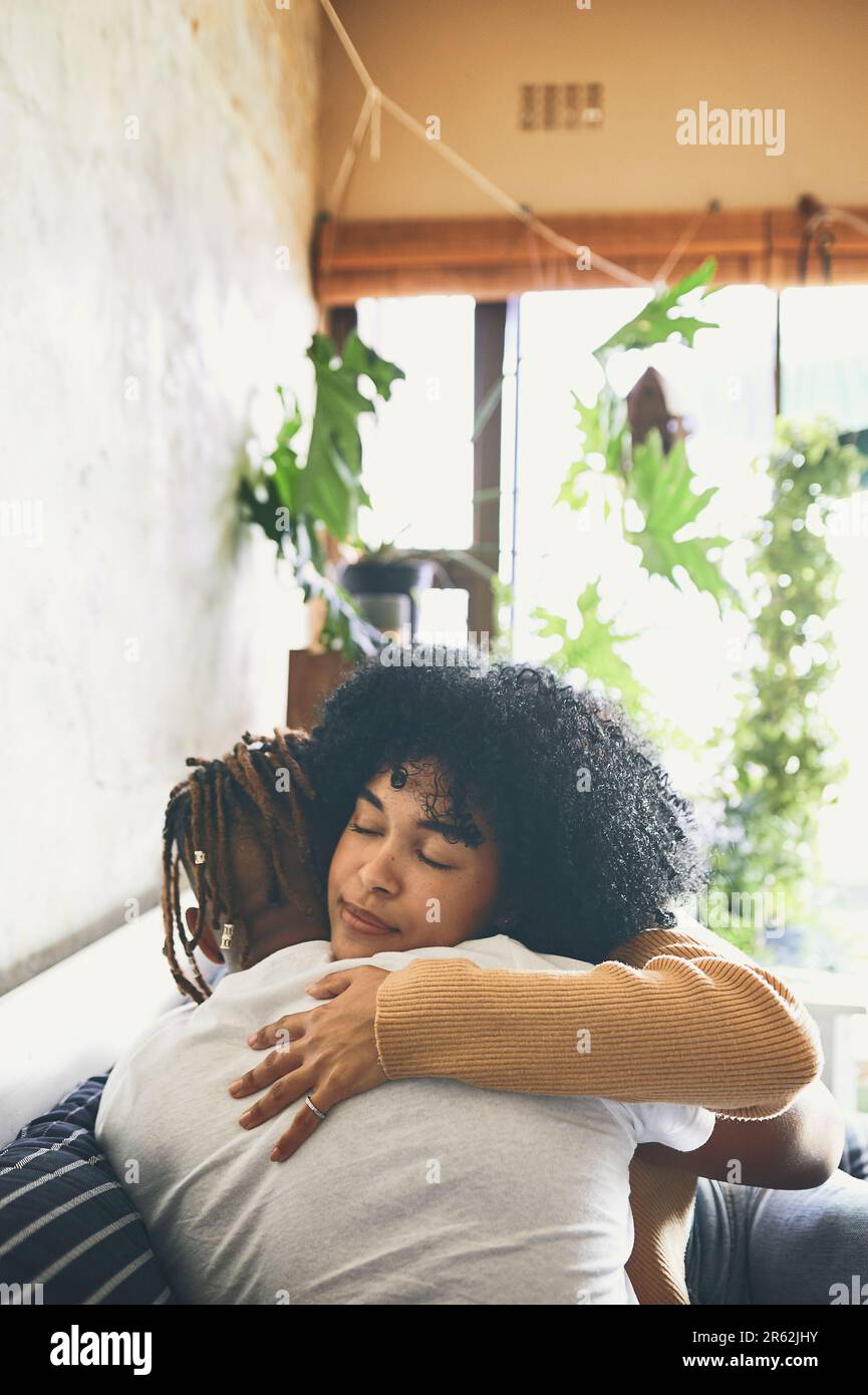 There for each other, through thick and thin. a young woman hugging her boyfriend at home Stock ...