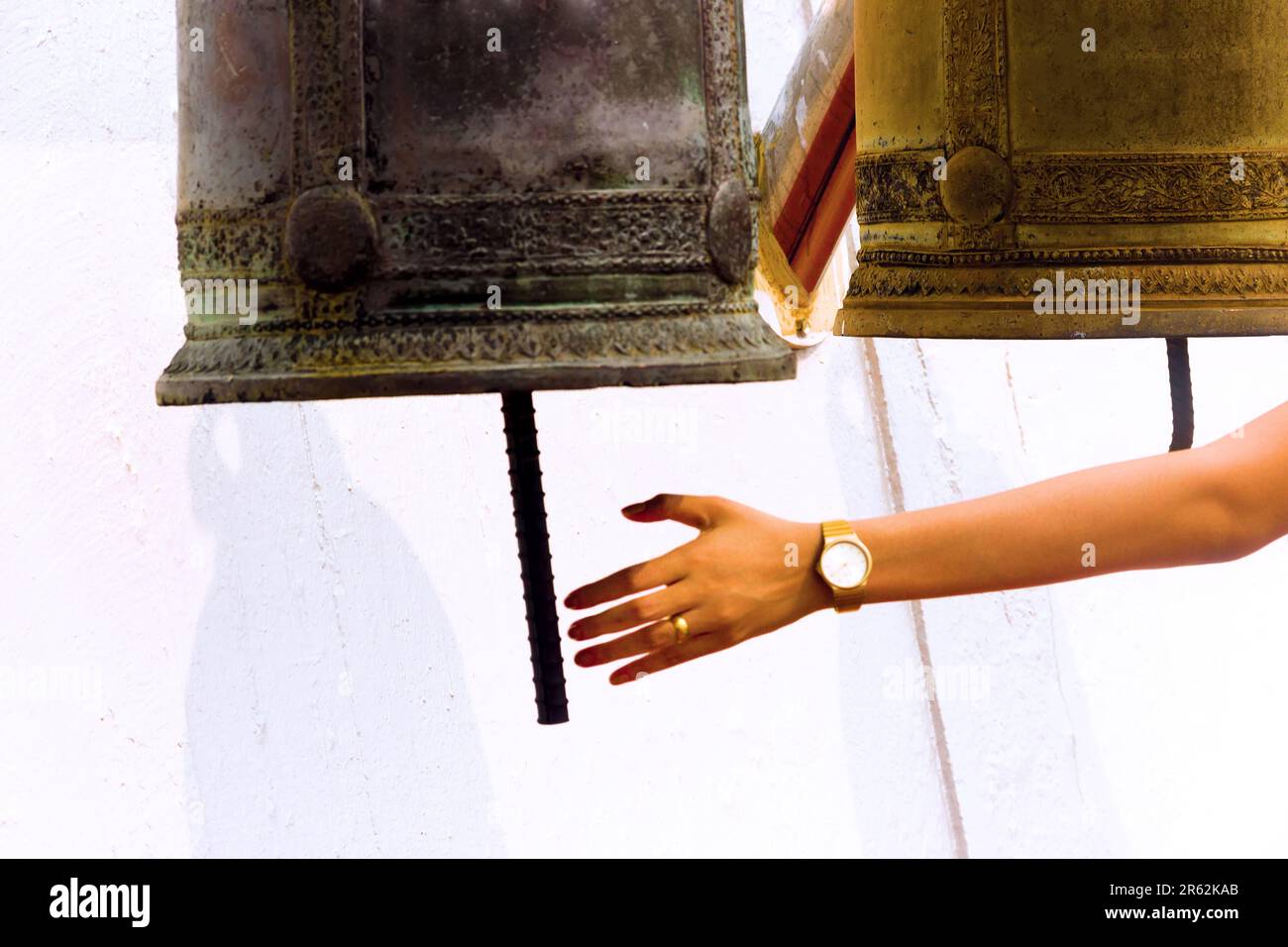 A girl (graceful hand of a European girl) knell a bell at a Buddhist ...