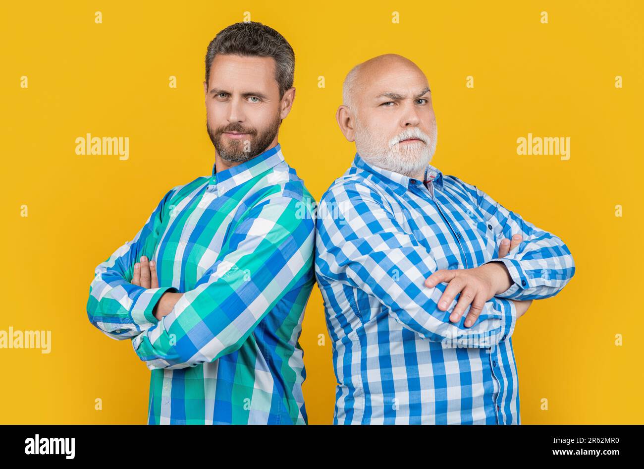 serious two generation family men isolated on yellow. two generation ...