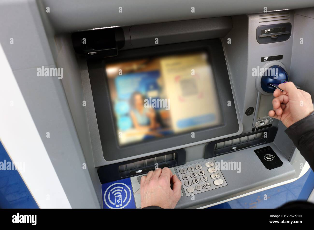A man making a transaction with a credit card at an ATM Automated ...