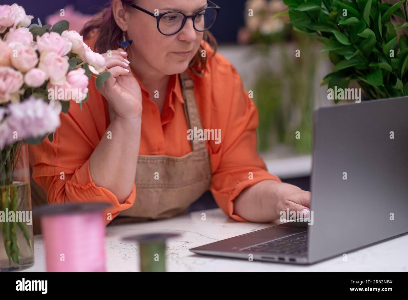florist owner in the flower shop accepts orders using laptop creates ...