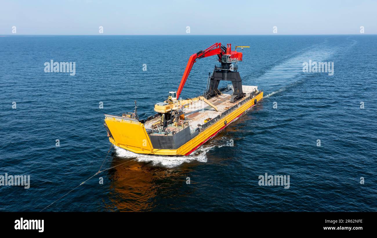 Yellow barge loaded with tracked harbour material handling cranes ...