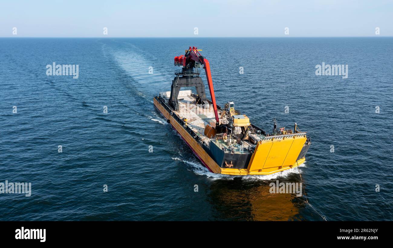 Yellow barge loaded with tracked harbour material handling cranes ...