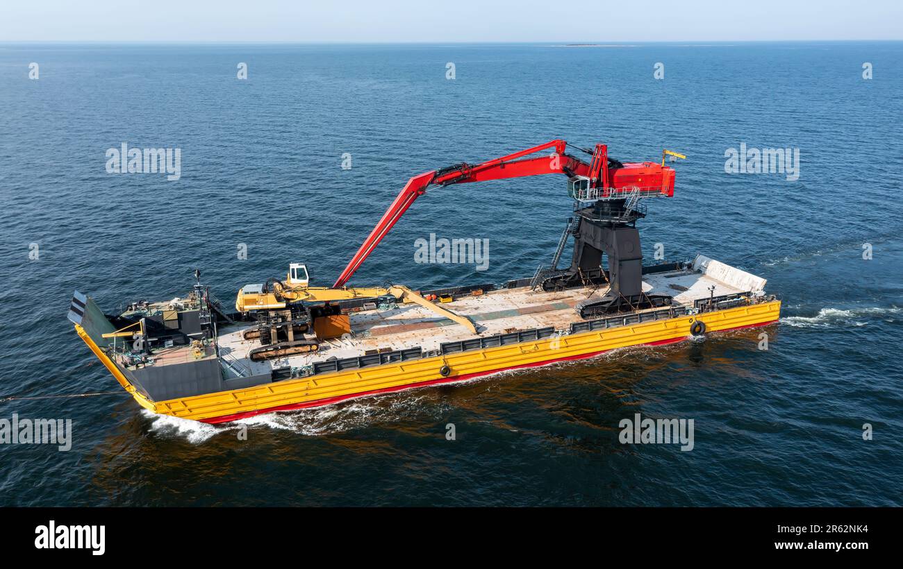 Yellow barge loaded with tracked harbour material handling cranes ...