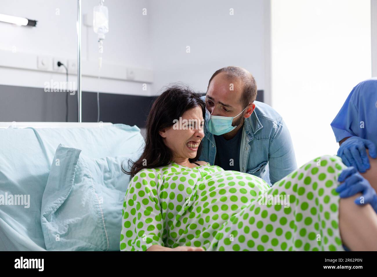 Pregnant woman pushing and screaming during childbirth, receiving ...