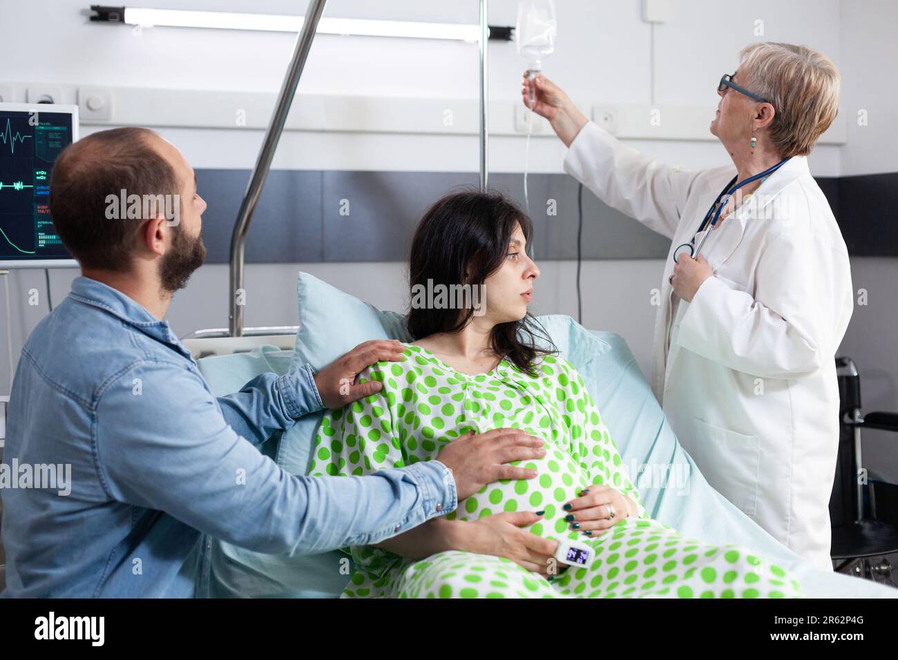 Senior medic checking iv drip bag, explaining caesarean surgery to ...