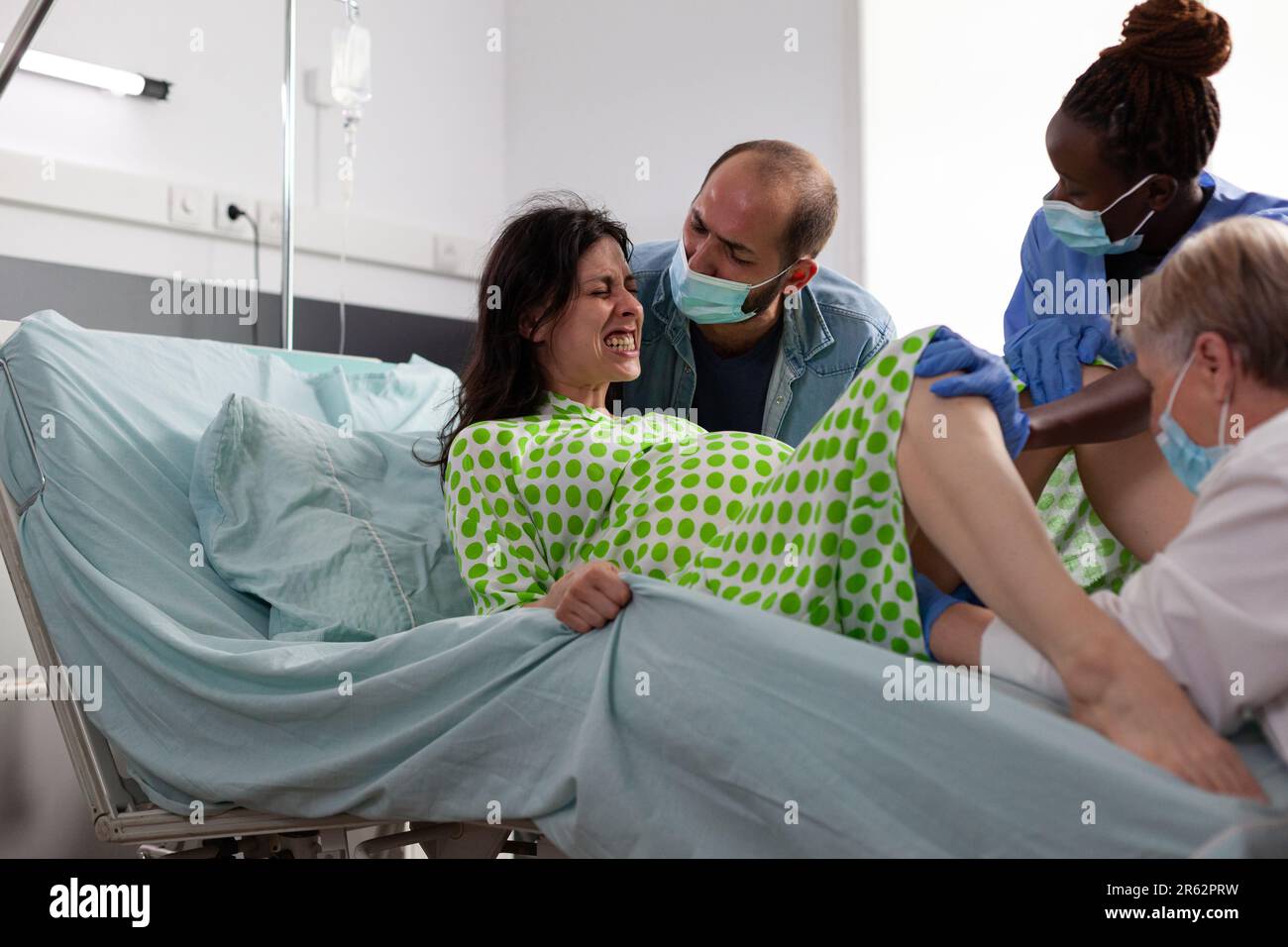 Woman having painful labor, medical team trying to delivery baby during ...