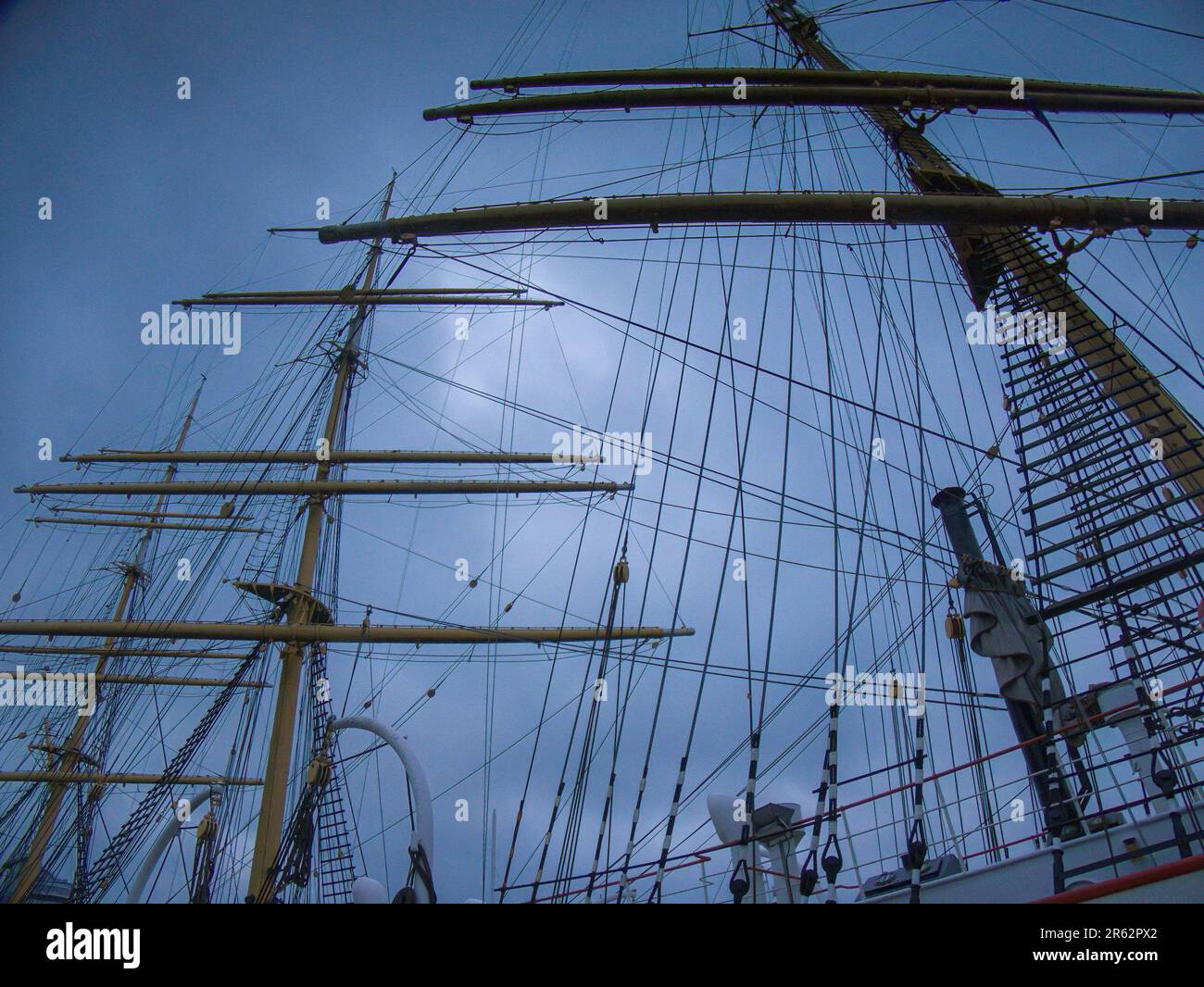 A line of large sailing vessels is seen in the water, with their tall ...