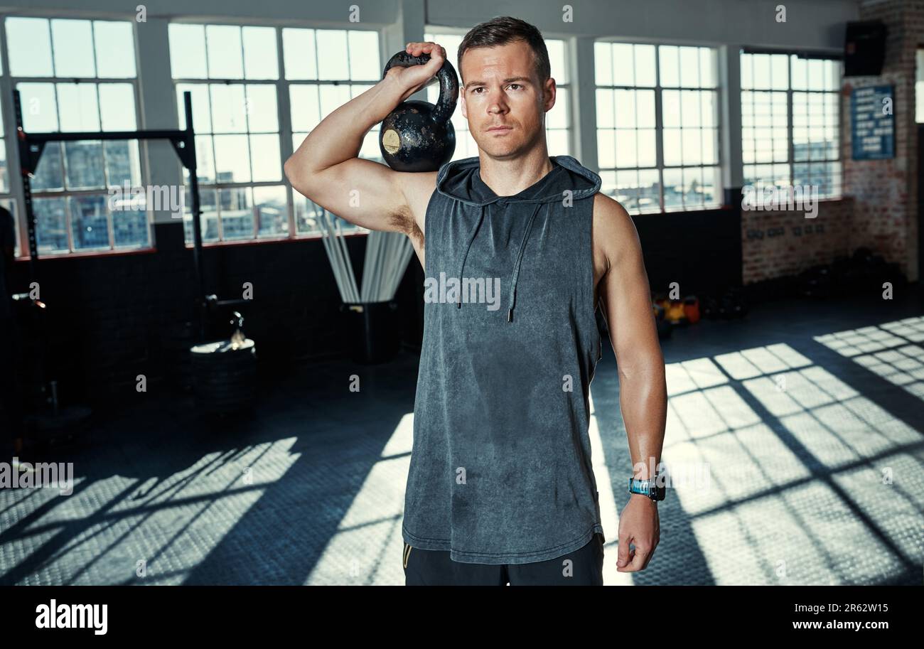 Weakness is a choice. a young man lifting kettlebells in a gym Stock ...