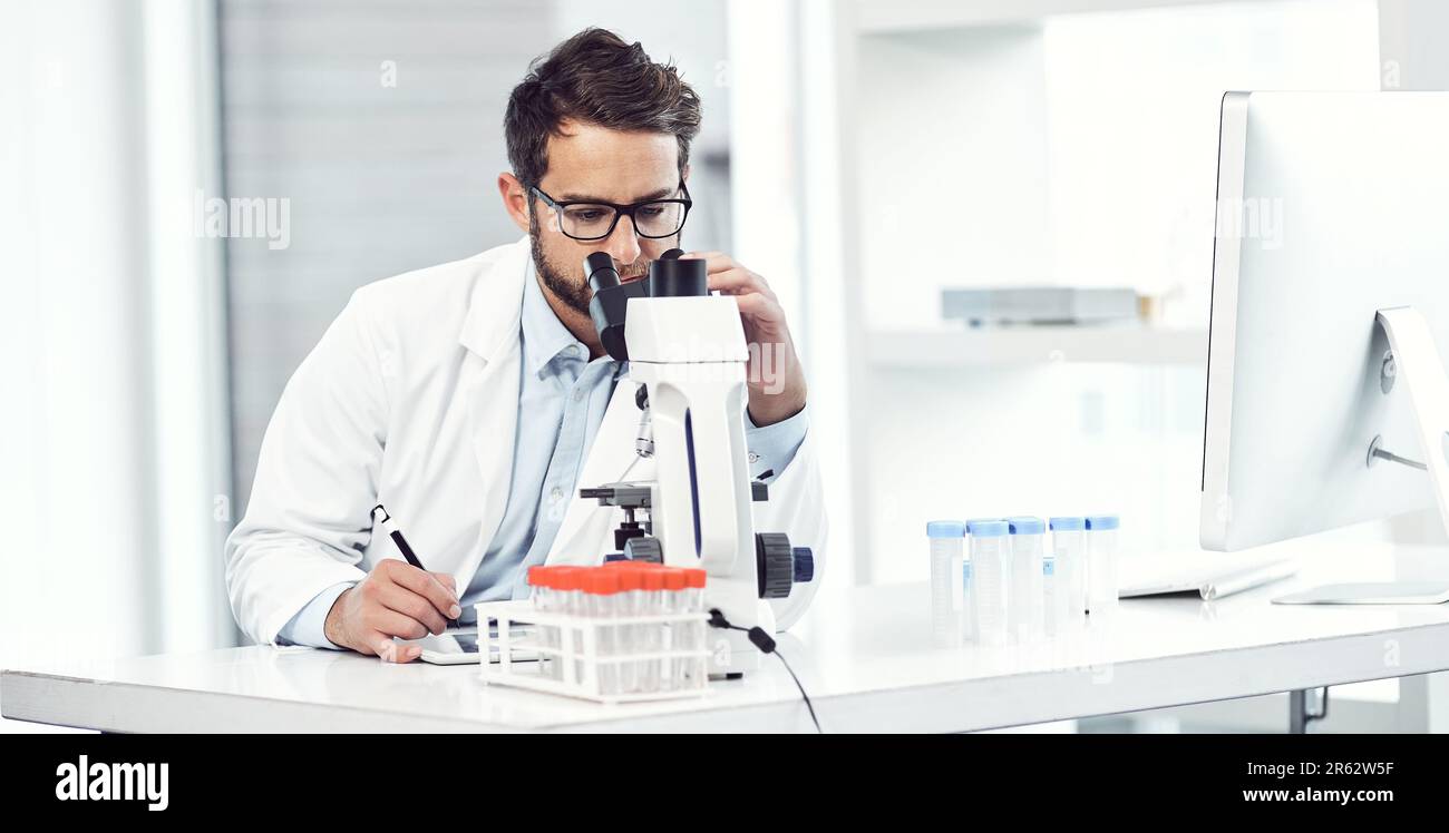 Observing the subject. a focused young male scientist making notes ...