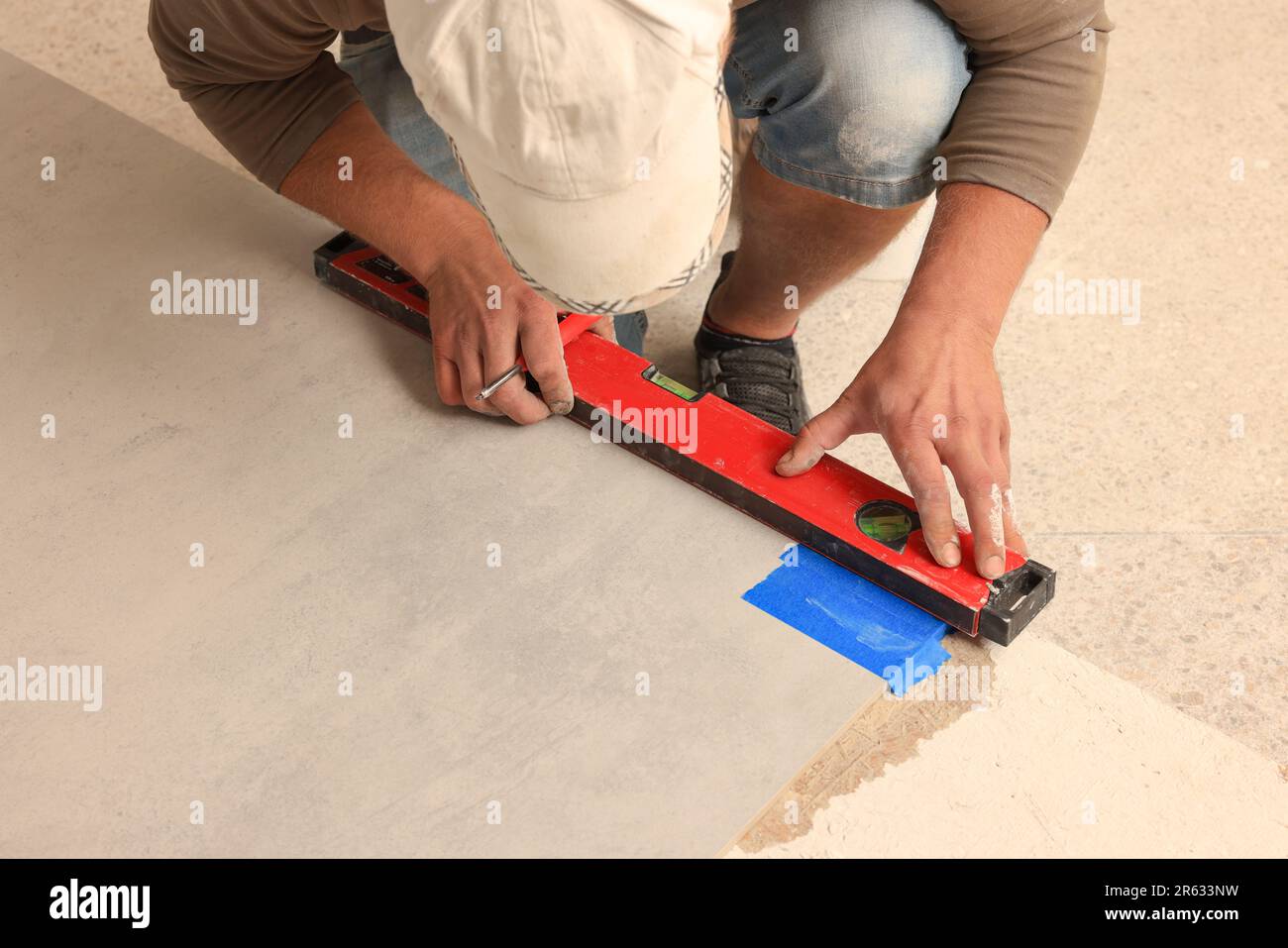 Worker measuring tile with building level indoors Stock Photo - Alamy