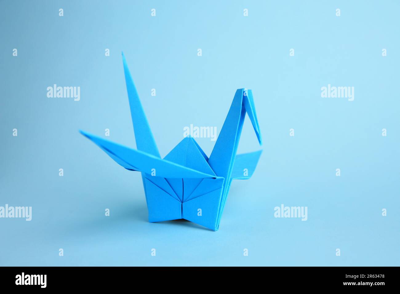 Origami art. Handmade paper crane on light blue background Stock Photo ...