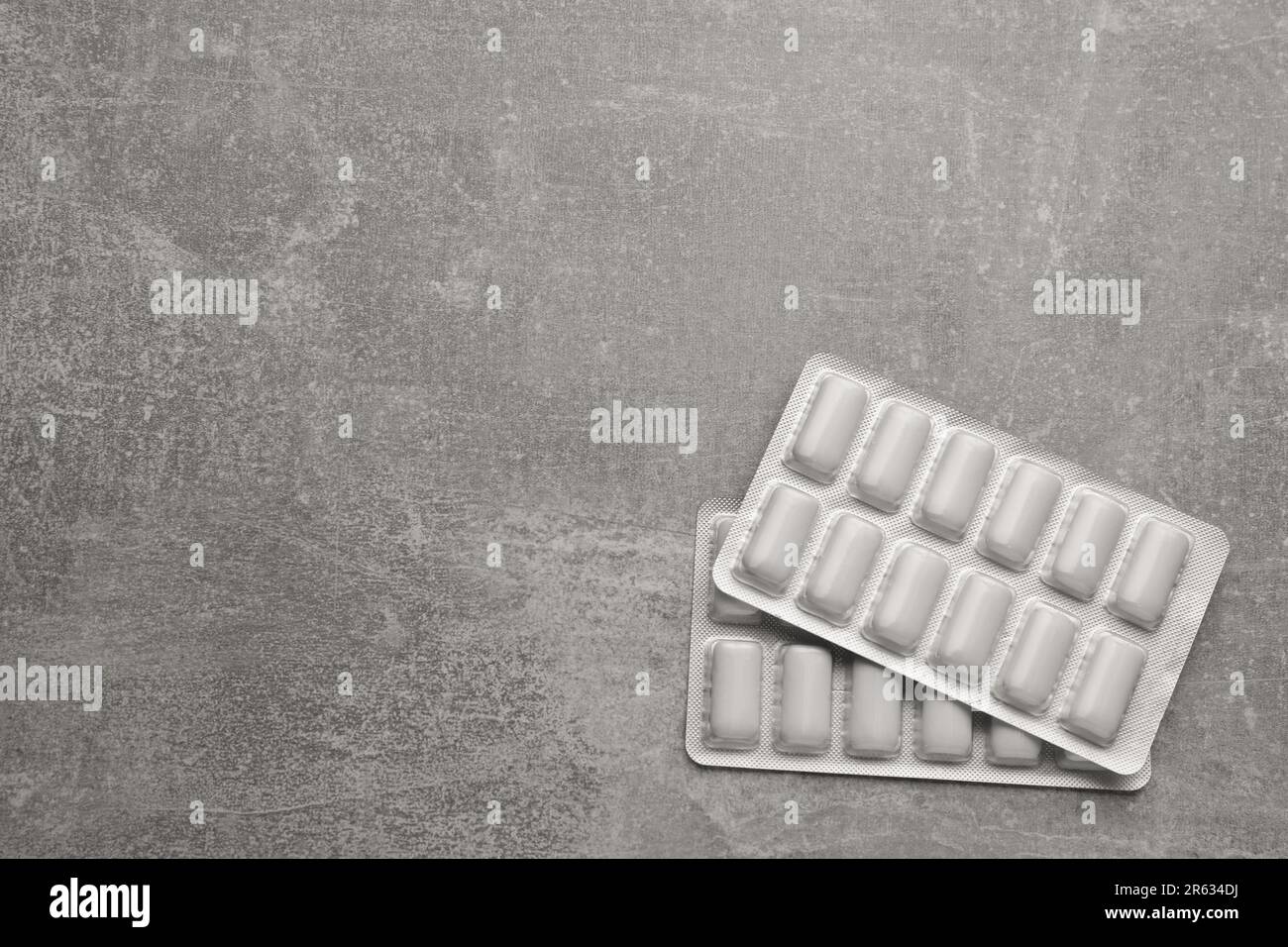 Blisters with chewing gums on light grey table, top view. Space for ...