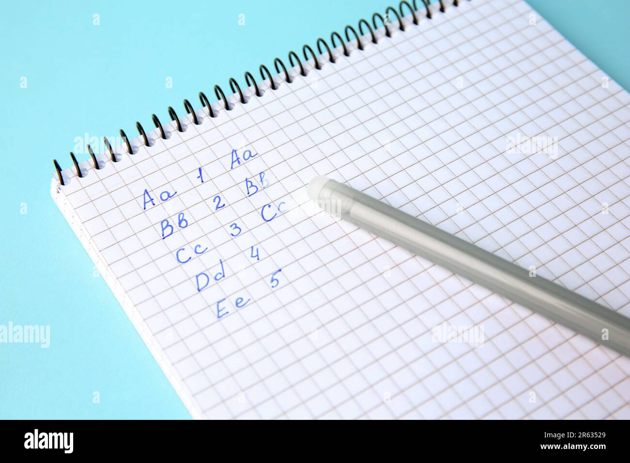 Letters and numbers written in notepad with erasable pen on light blue ...