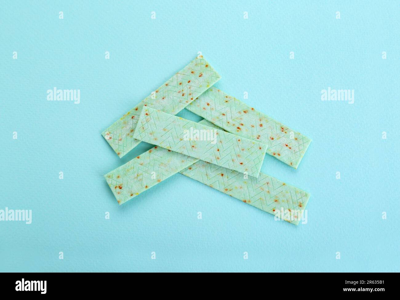 Many sticks of tasty chewing gum on light blue background, flat lay ...