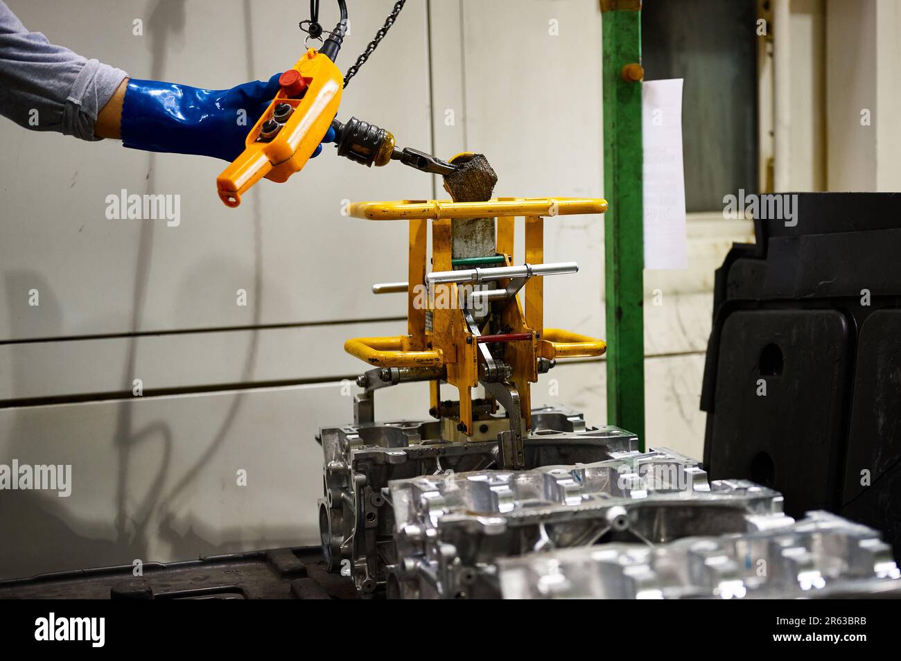 Warehouse of an automobile plant, a worker lifts the cylinder block of ...