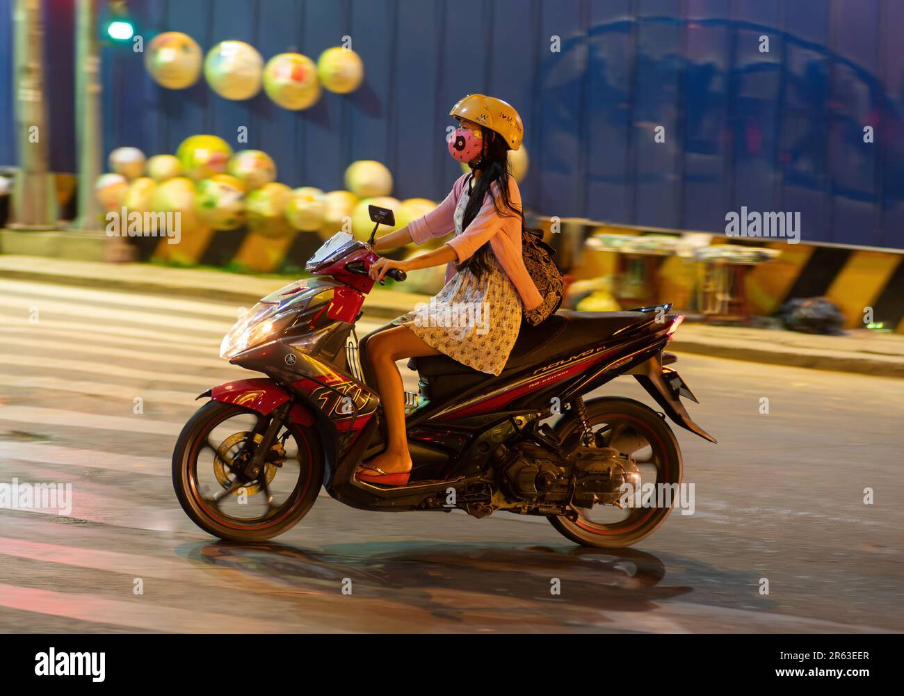 Young, Vietnamese woman driving her motorbike through the streets of Ho ...