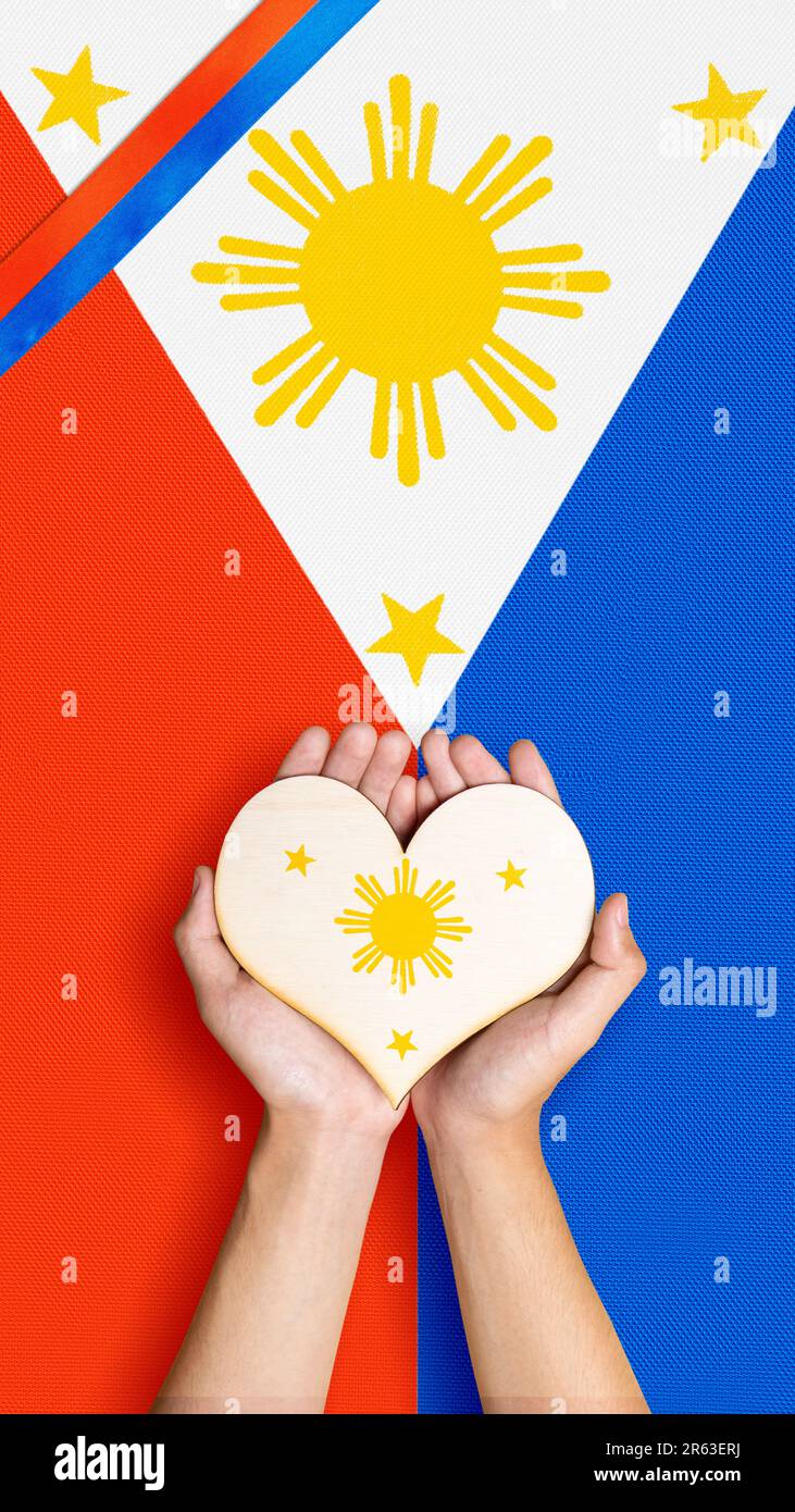 A human hand is holding a heart with the Philippine flag color ...