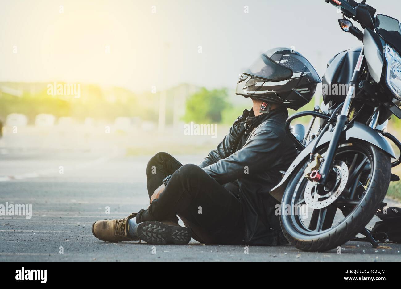 Biker sitting next to his motorcycle on the road. Male motorcyclist ...