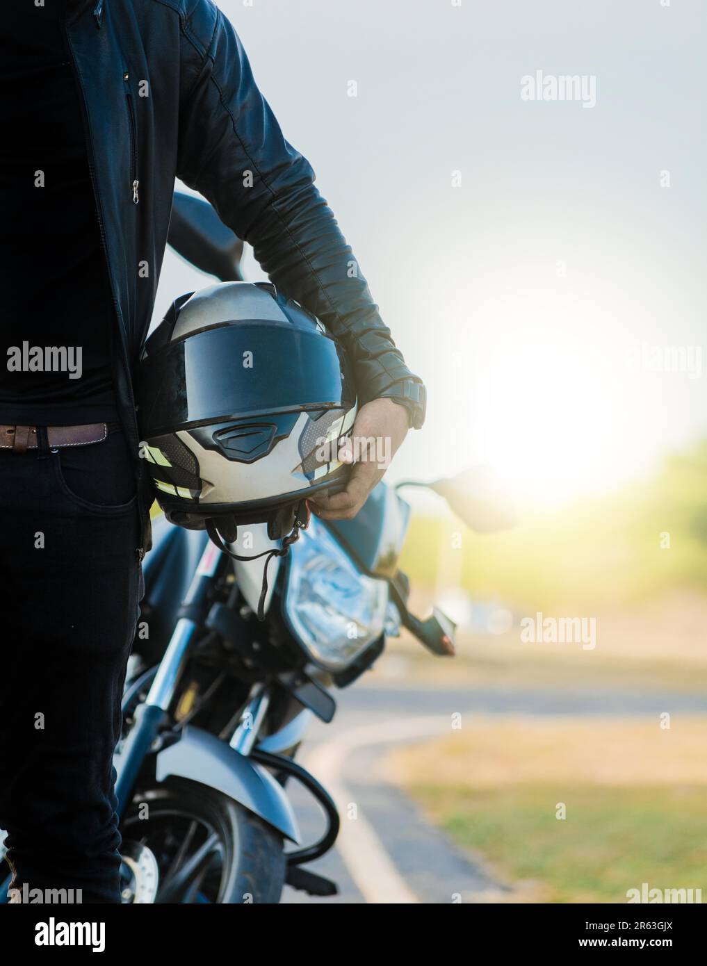 Motorcycle safety helmet concept. Unrecognizable biker holding helmet next to motorbike near the ...
