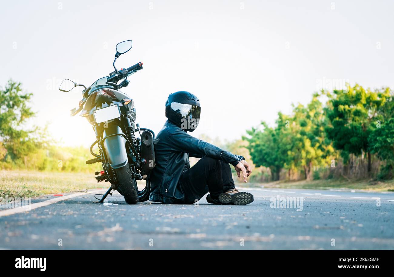Male biker sitting next to his motorcycle on the road. Male ...