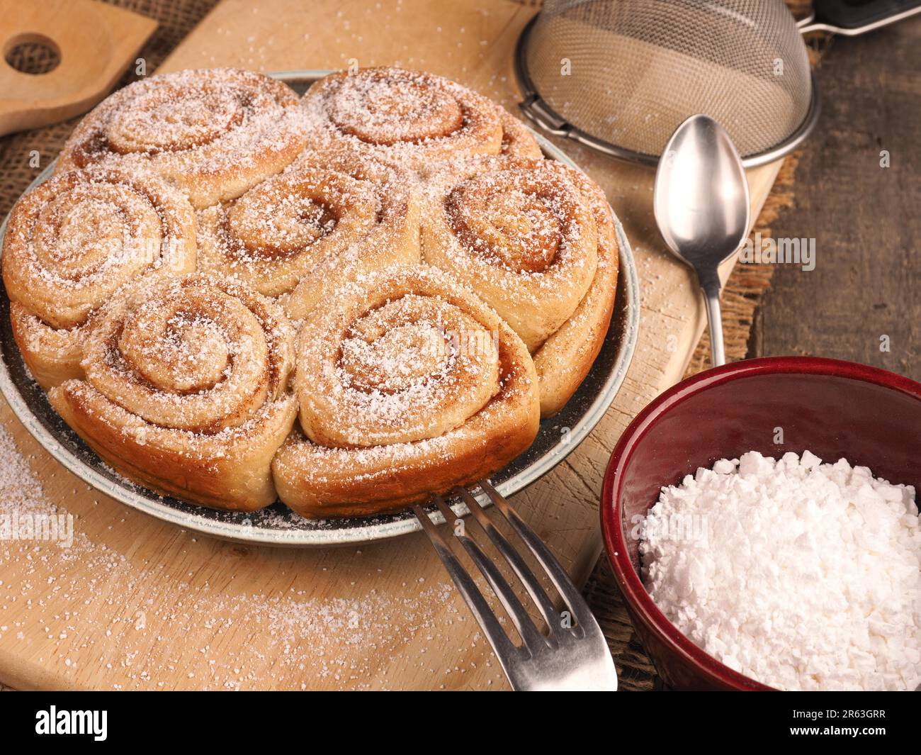 Homemade cinnamon snails with kitchen utensils on a rustic wooden ...