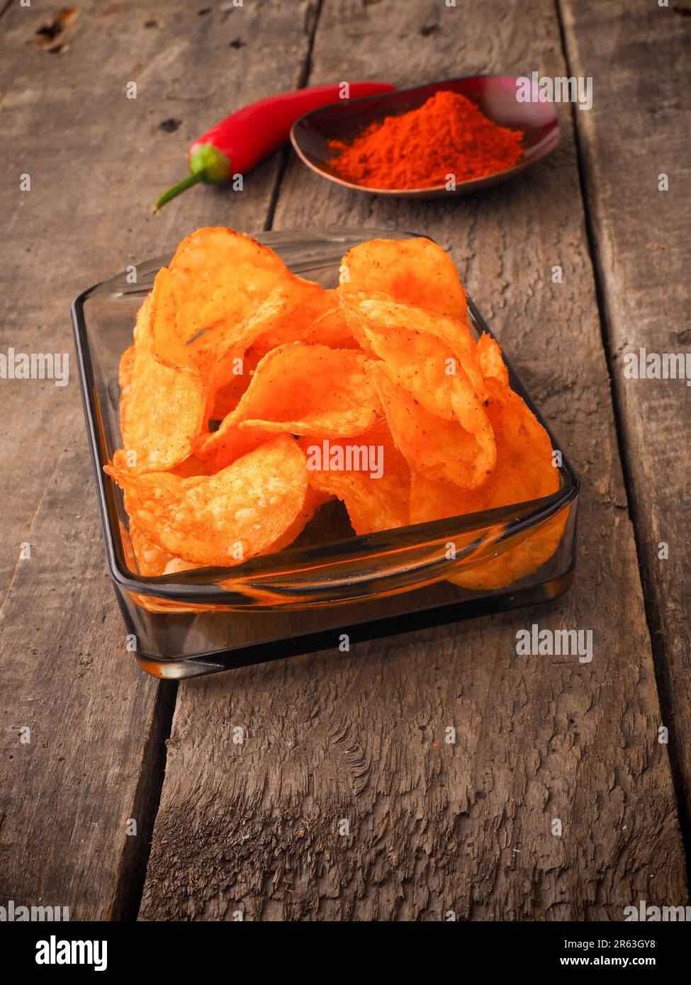 Spicy potato chips with a red pepperoni on a rustic wooden kitchen ...