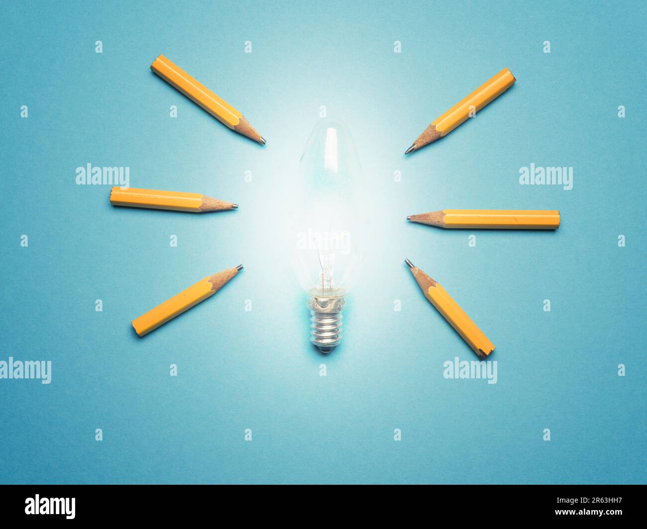 A glowing light bulb with 6 pencils as light rays, New ideas or creativity concept on blue ...