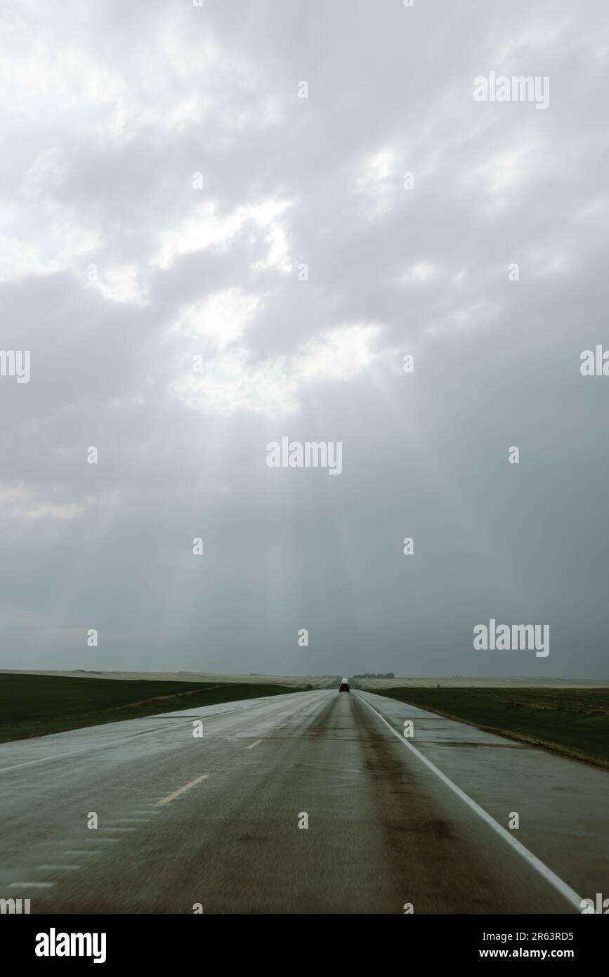 A grey, cloudy sky looms overhead, casting a shadow over the road and ...