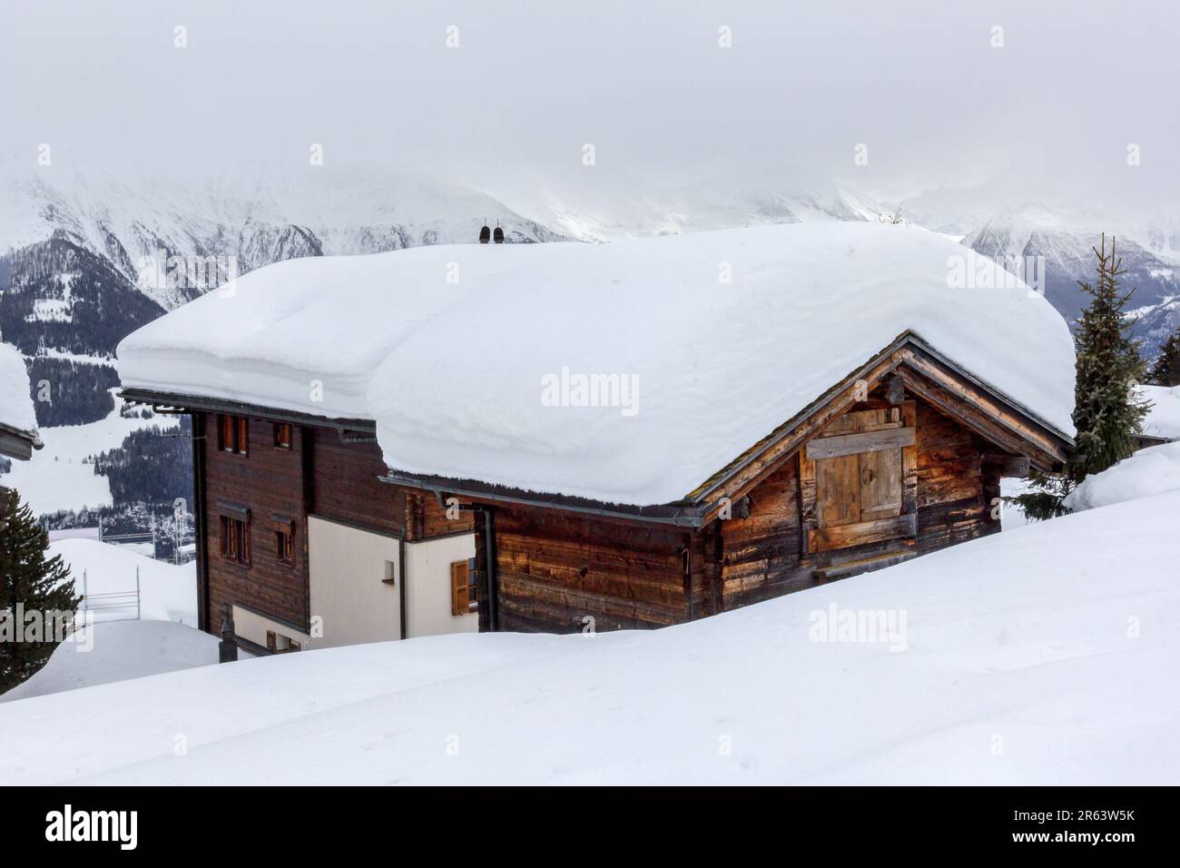 Alpine chalet sunk in deep snow in winter with thick snow on roof in ...