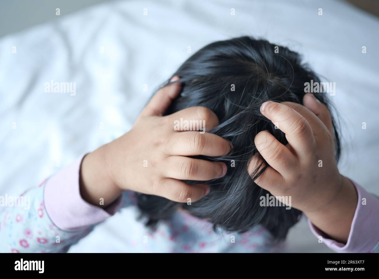child scratching head sitting on the bed Annoying itch Stock Photo - Alamy