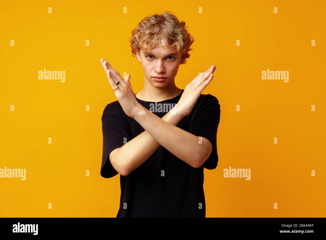 Photo of young strict man showing arms denial symbol against yellow ...