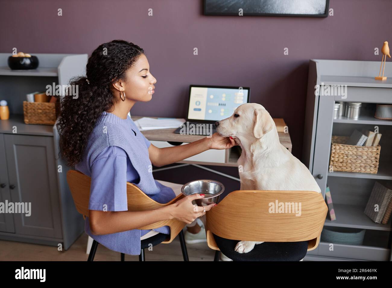 Side view portrait of young black woman petting cute dog sitting on ...