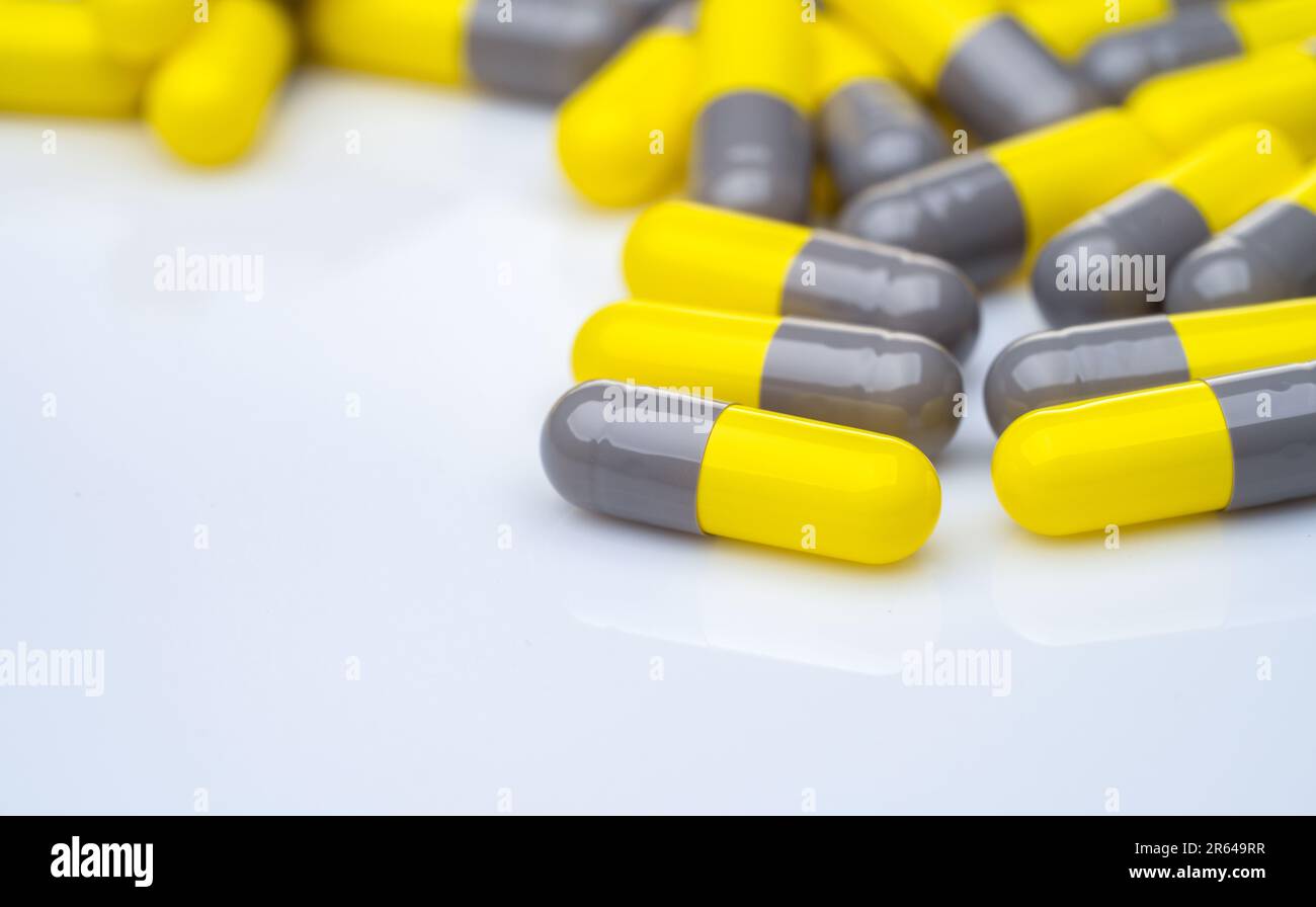 Closeup yellow and gray capsule pills on white background. Prescription ...